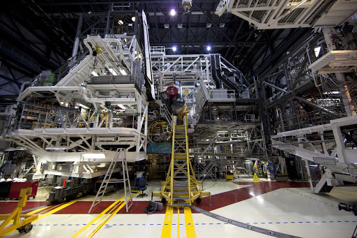 Technicians monitor the progress as a large crane lifts the right ...